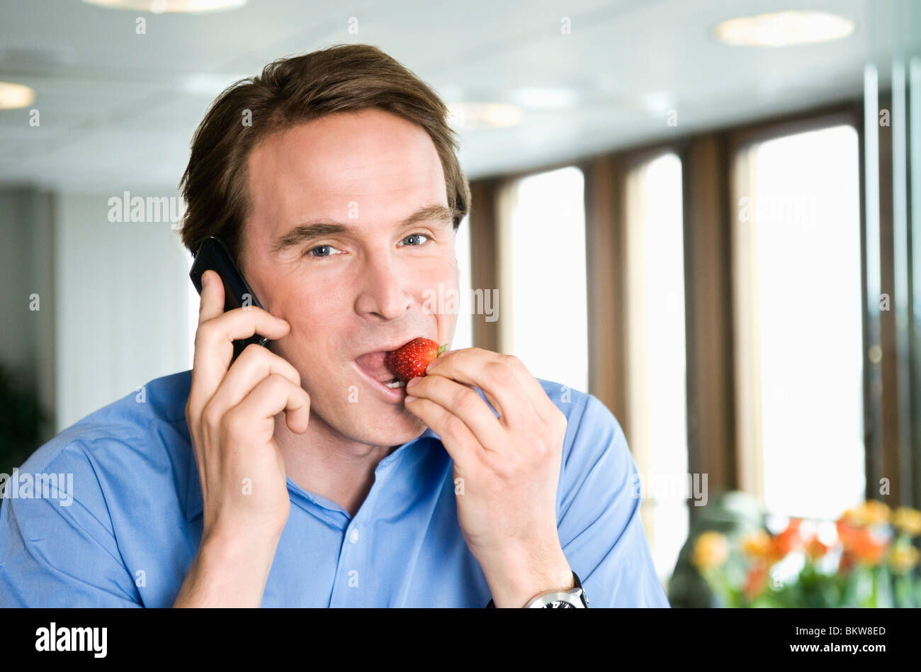 Man talking in phone and eating strawberry Stock Photo - Alamy