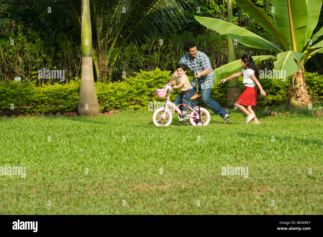 Son learning bicycle with her father, daughter chasing Stock Photo - Alamy