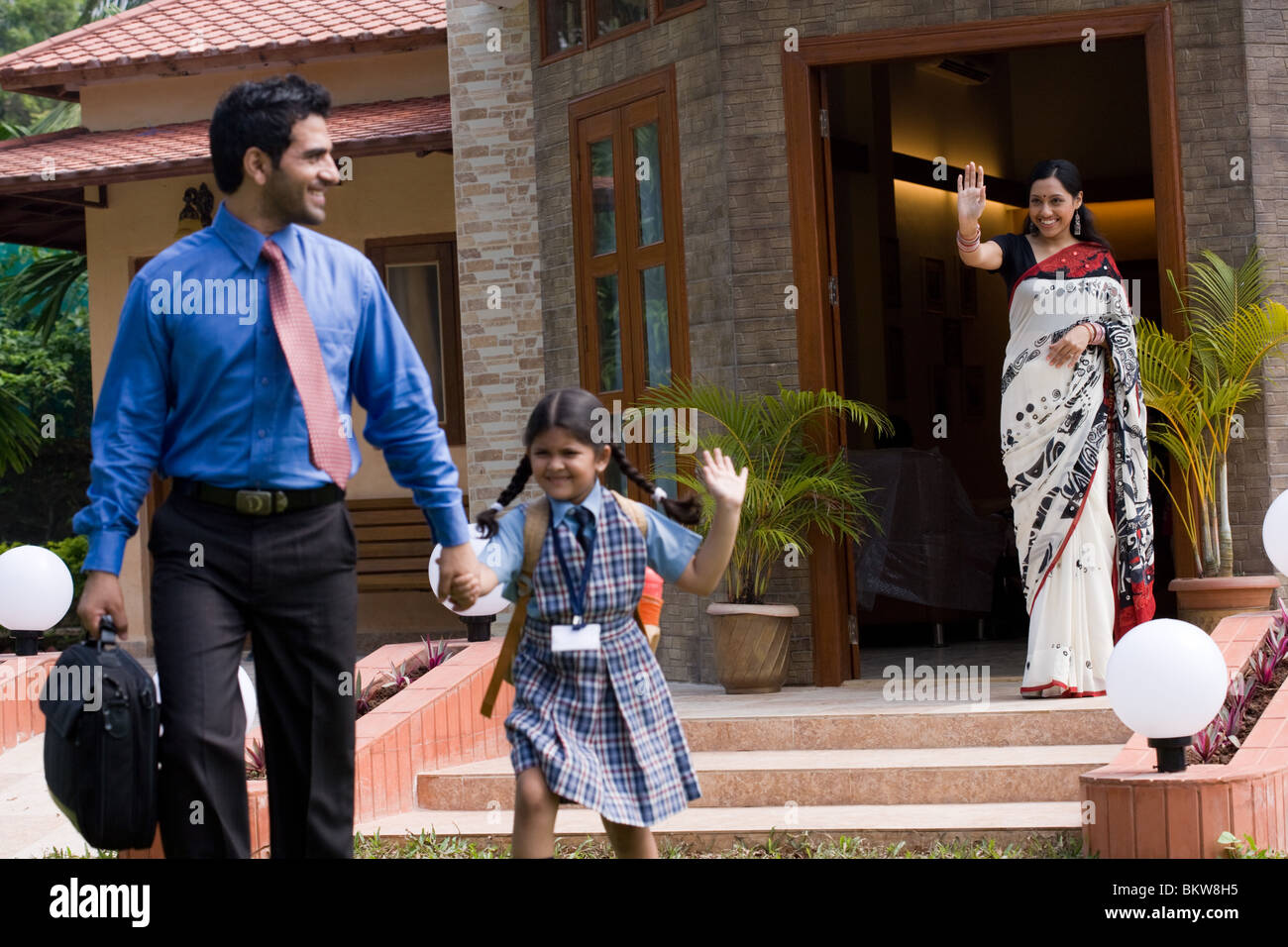 Schoolgirl (8-9) with father waving off to mother, smiling Stock Photo ...