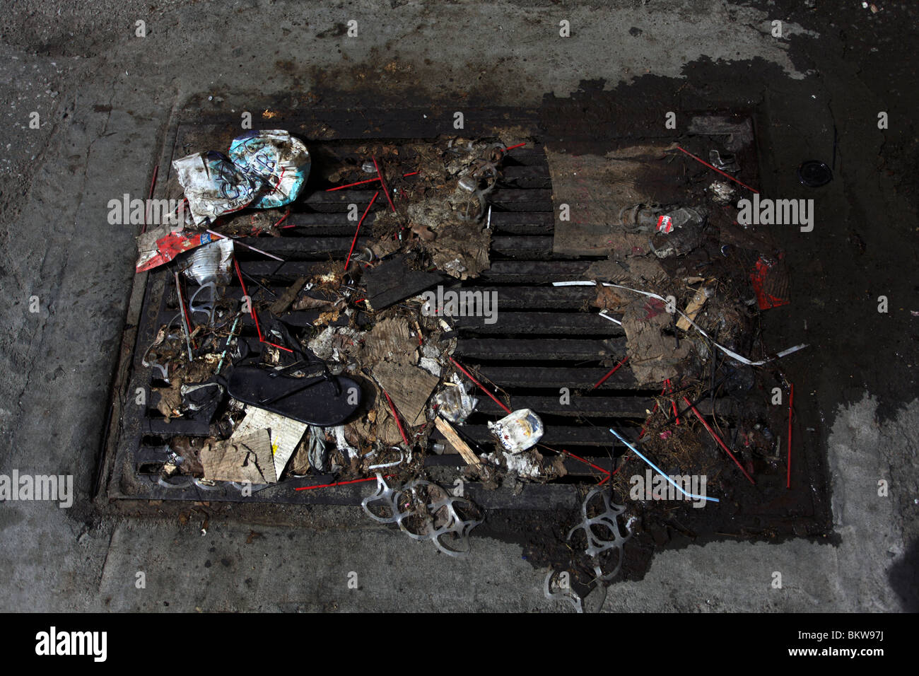 Trash on street surface grate Stock Photo - Alamy