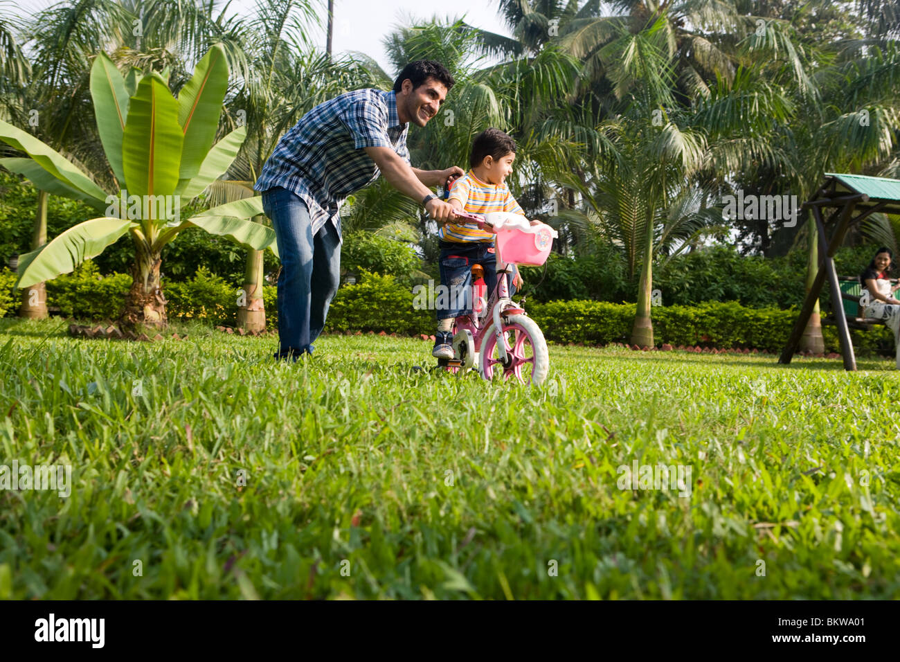 Son learning bicycle with her father, daughter chasing Stock Photo - Alamy