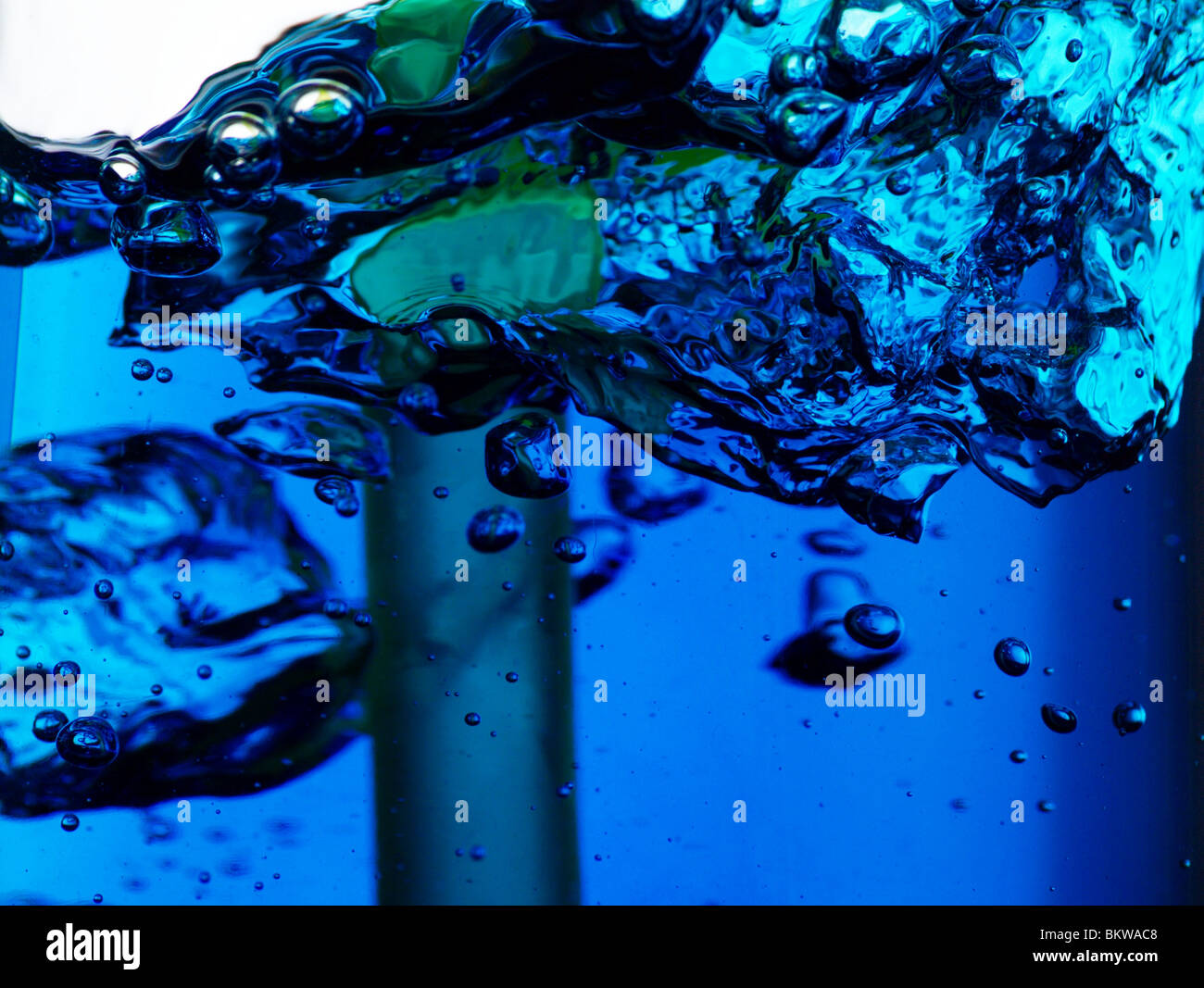 A straw bubbling blue water Stock Photo - Alamy