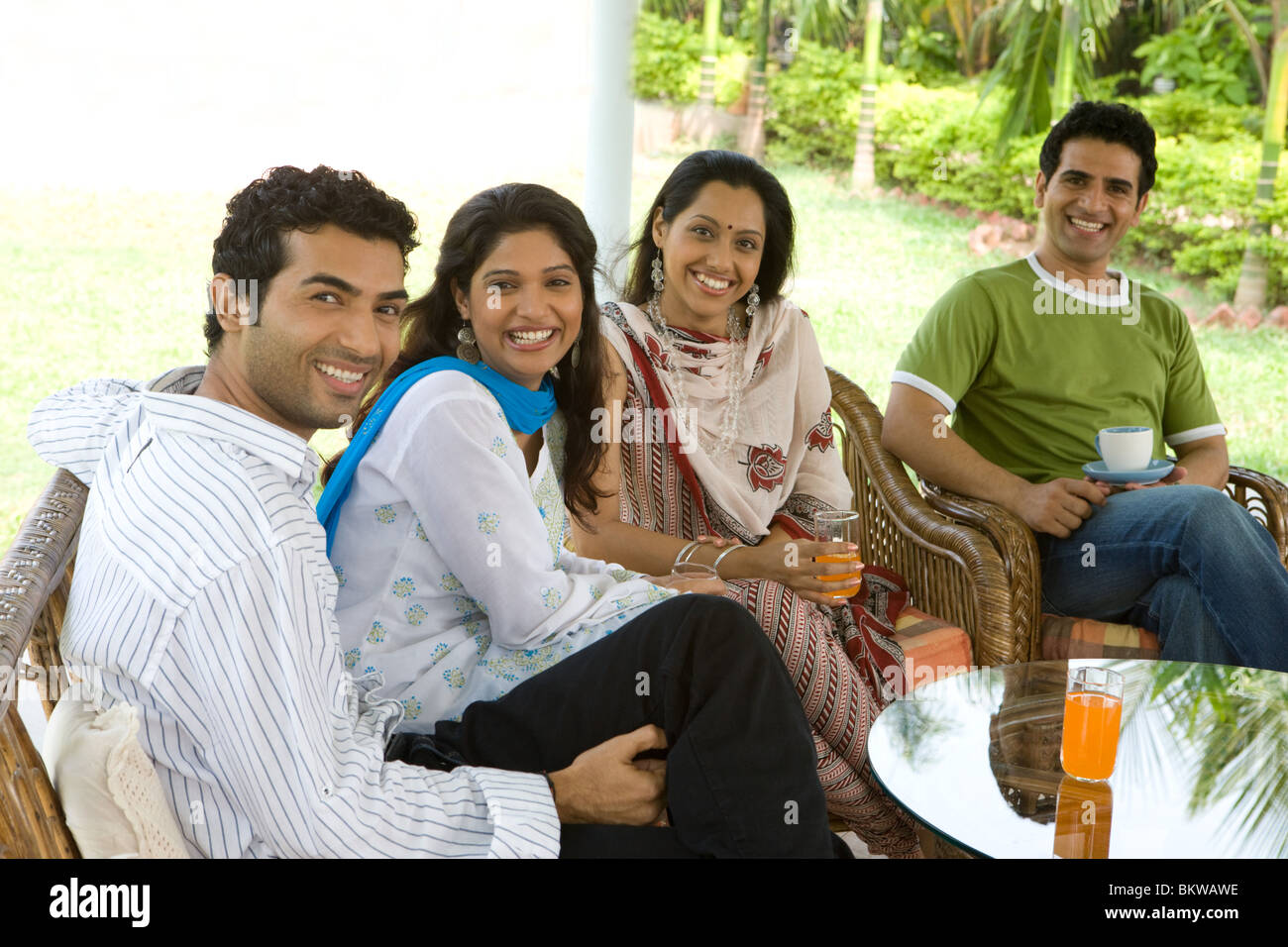 Two couples sitting in the garden, smiling Stock Photo - Alamy
