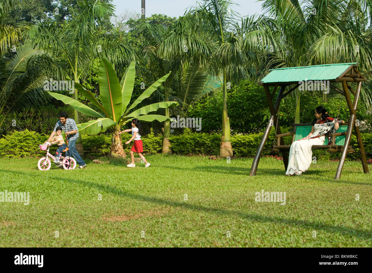 Son learning bicycle with her father, daughter chasing Stock Photo - Alamy