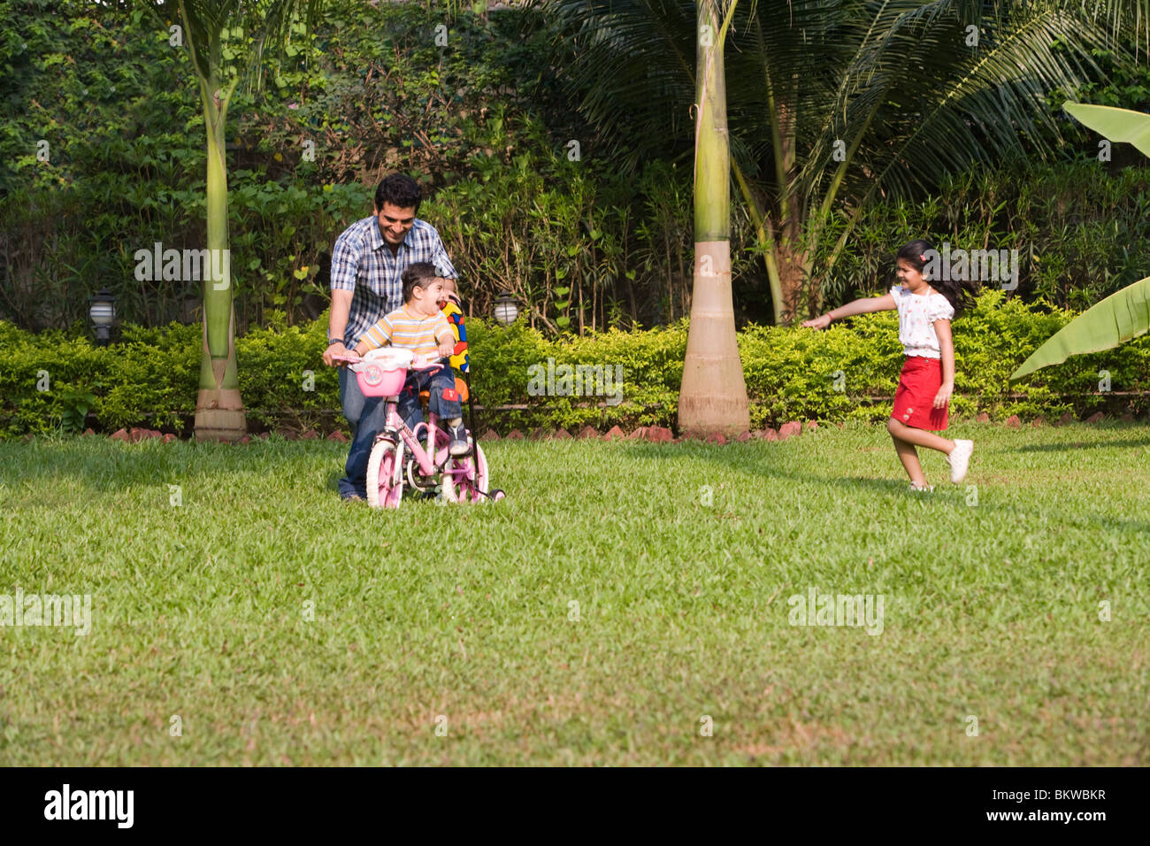 Son learning bicycle with her father, daughter chasing Stock Photo - Alamy