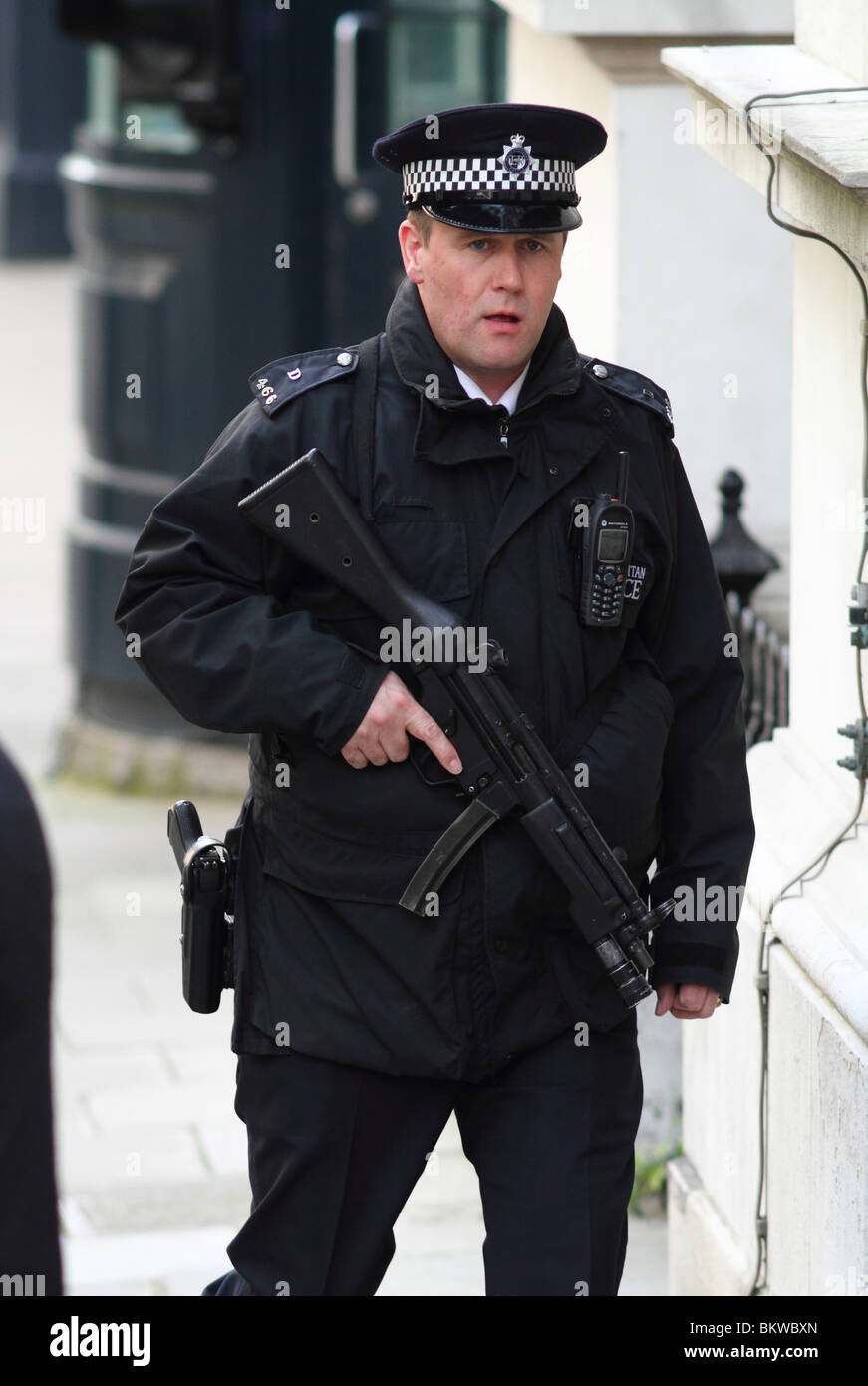 An armed police officer with a hand gun and automatic weapon outside ...