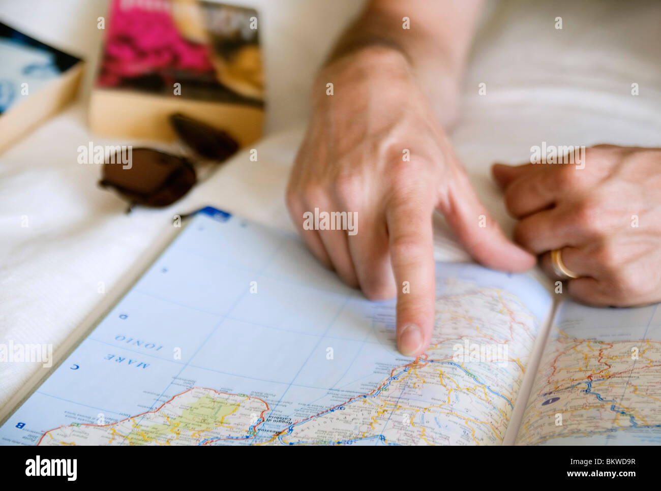 Finger of man pointing at location on open map Stock Photo - Alamy