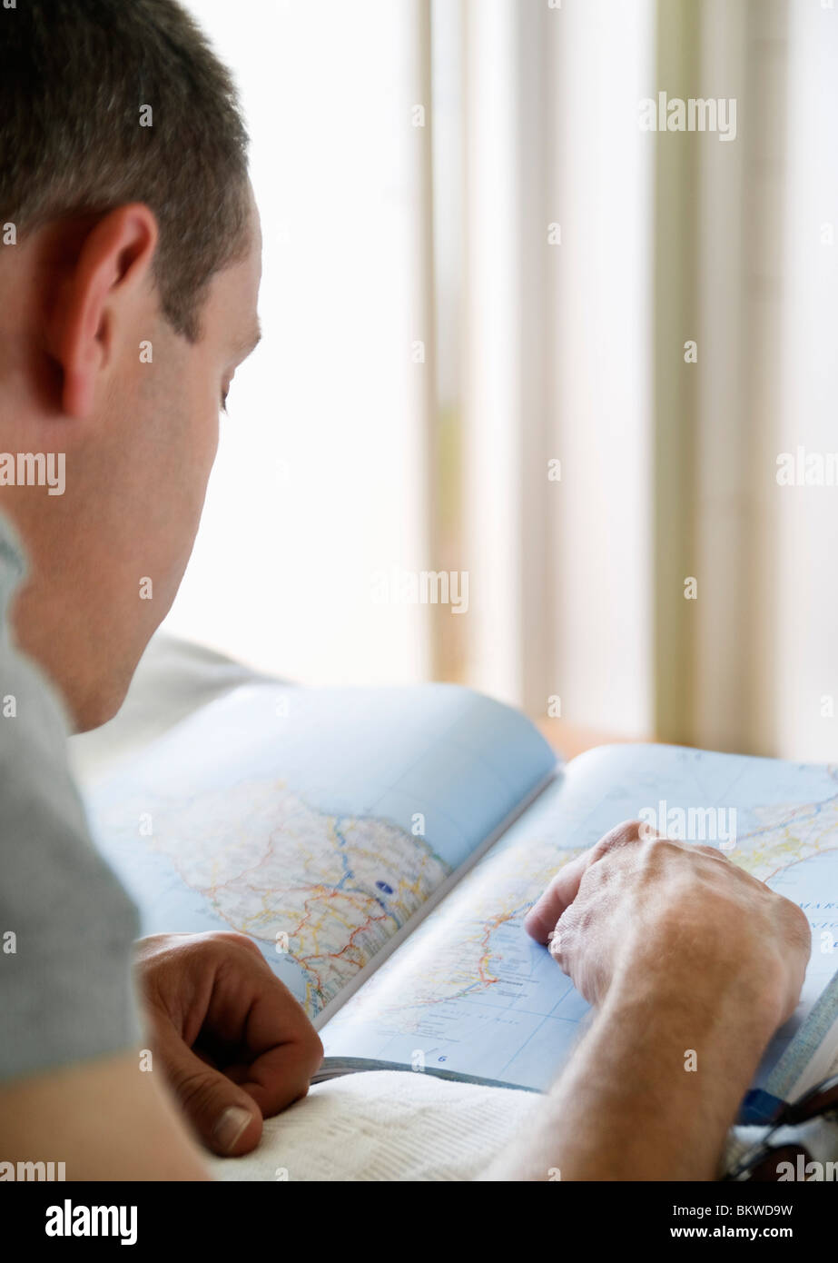 View over shoulder of man pointing at location on map Stock Photo - Alamy