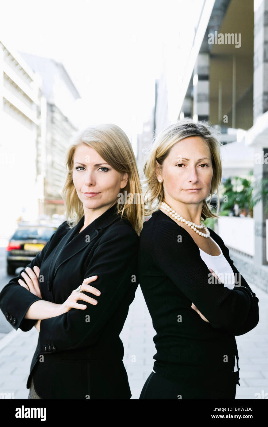 Two businesswomen standing back-to-back Stock Photo - Alamy