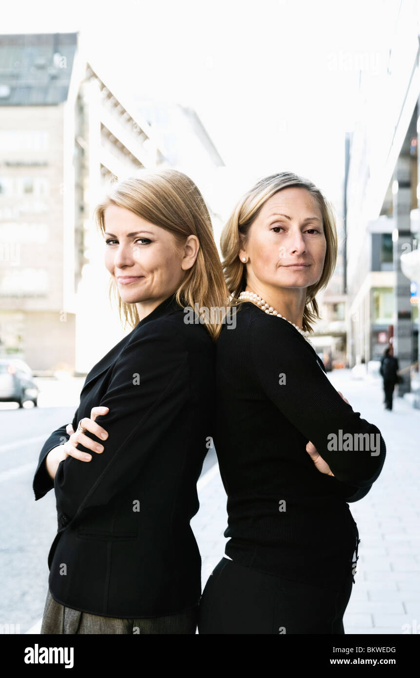 Two businesswomen standing back-to-back Stock Photo - Alamy