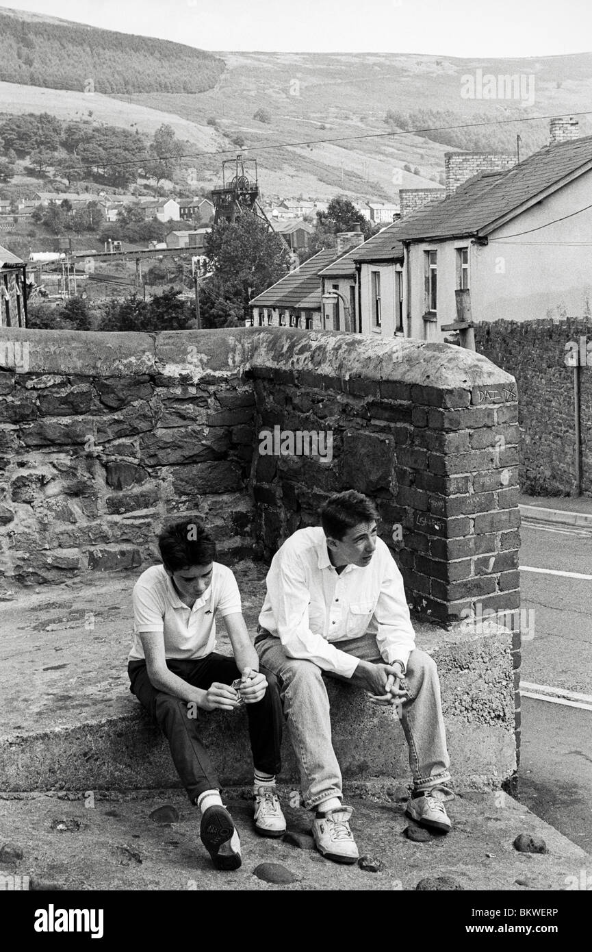 Two teenagers sat on street corner overlooking colliery in village of ...