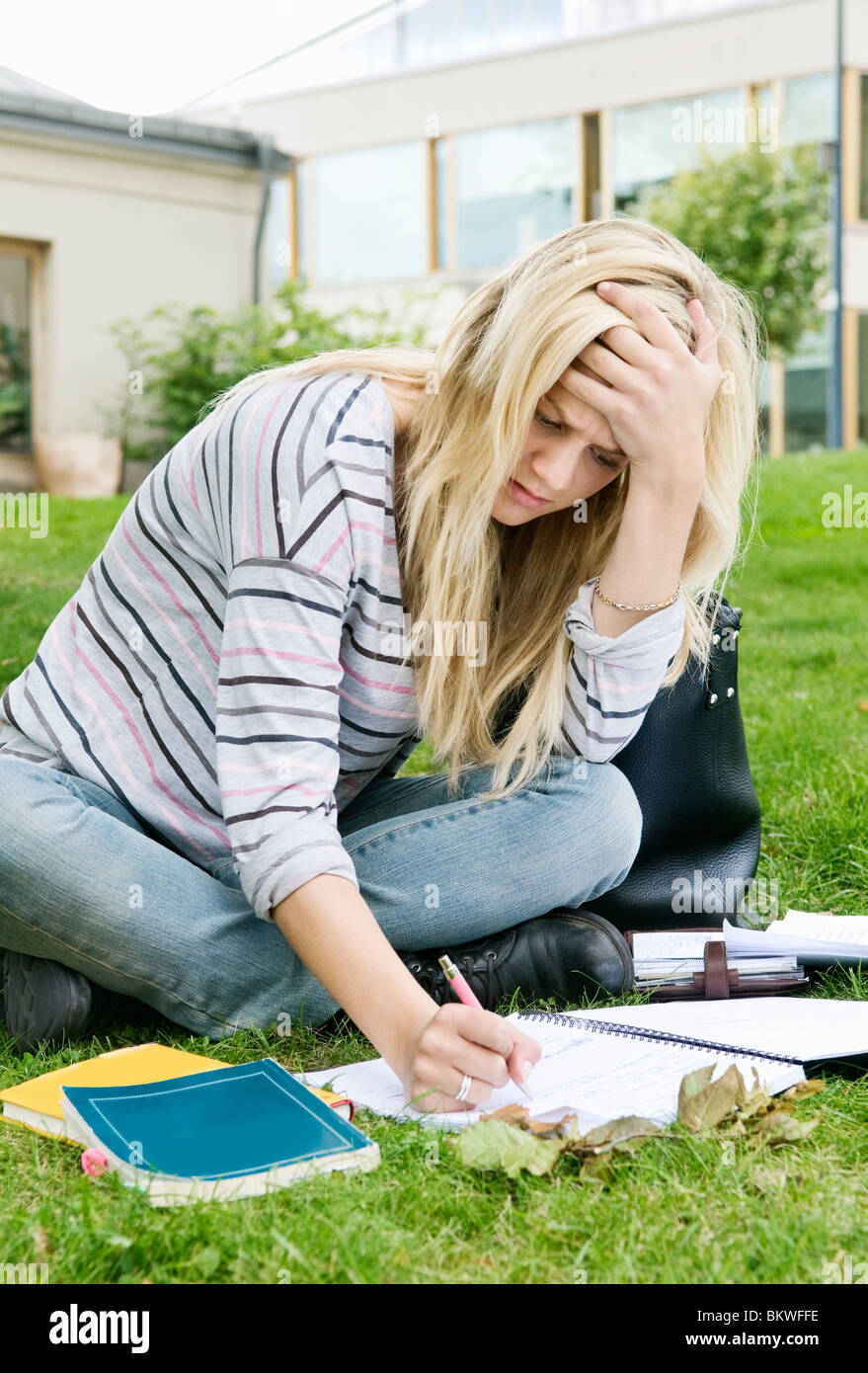Concentrated woman sitting on lawn writing in notepad Stock Photo - Alamy