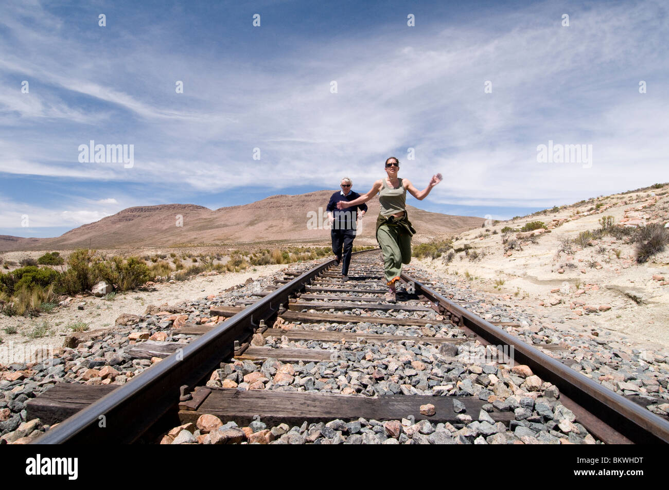 man and woman running down railway track Stock Photo - Alamy