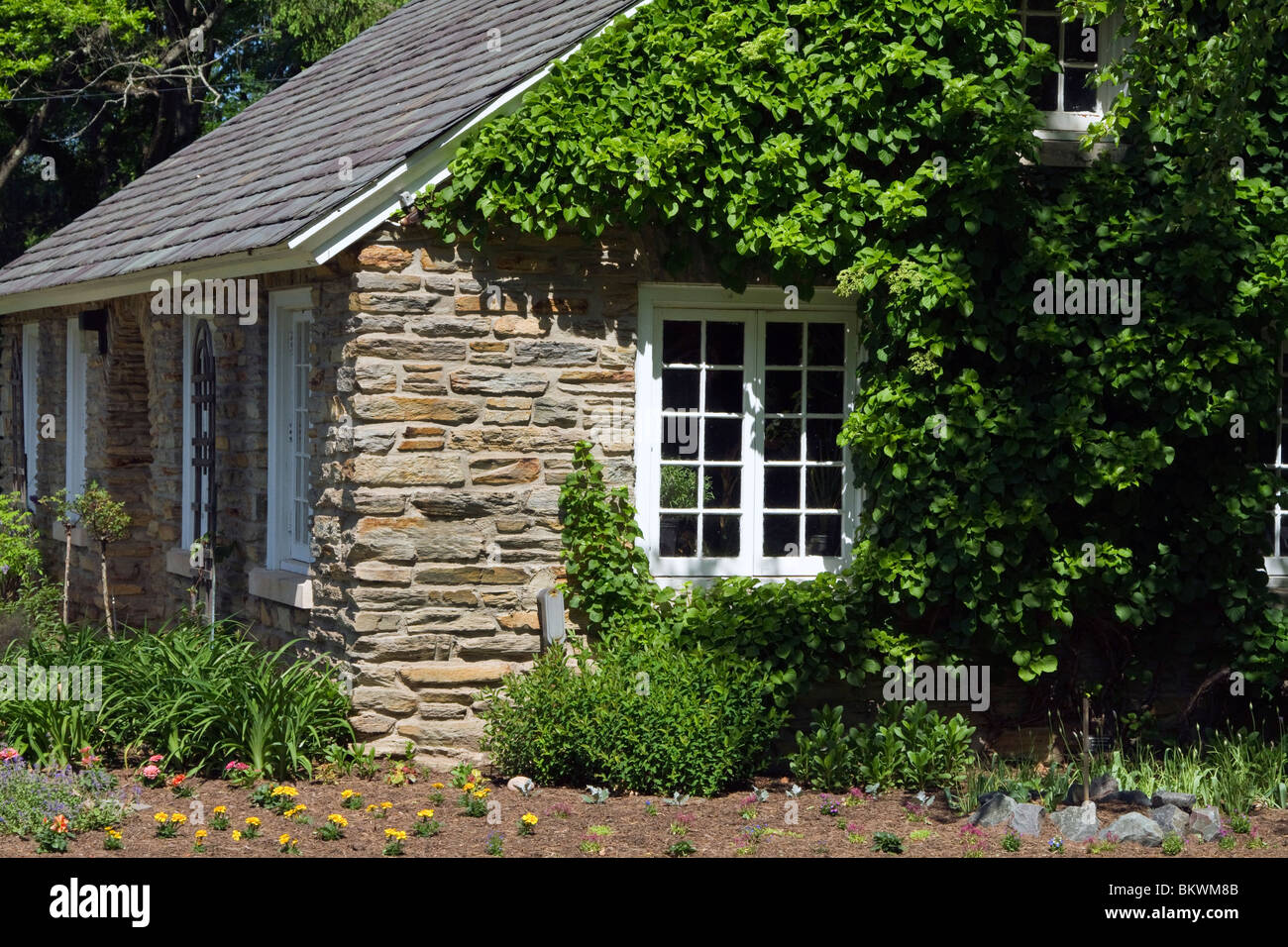 The gable end of a country cottage with ceder shakes stone chimney and ...