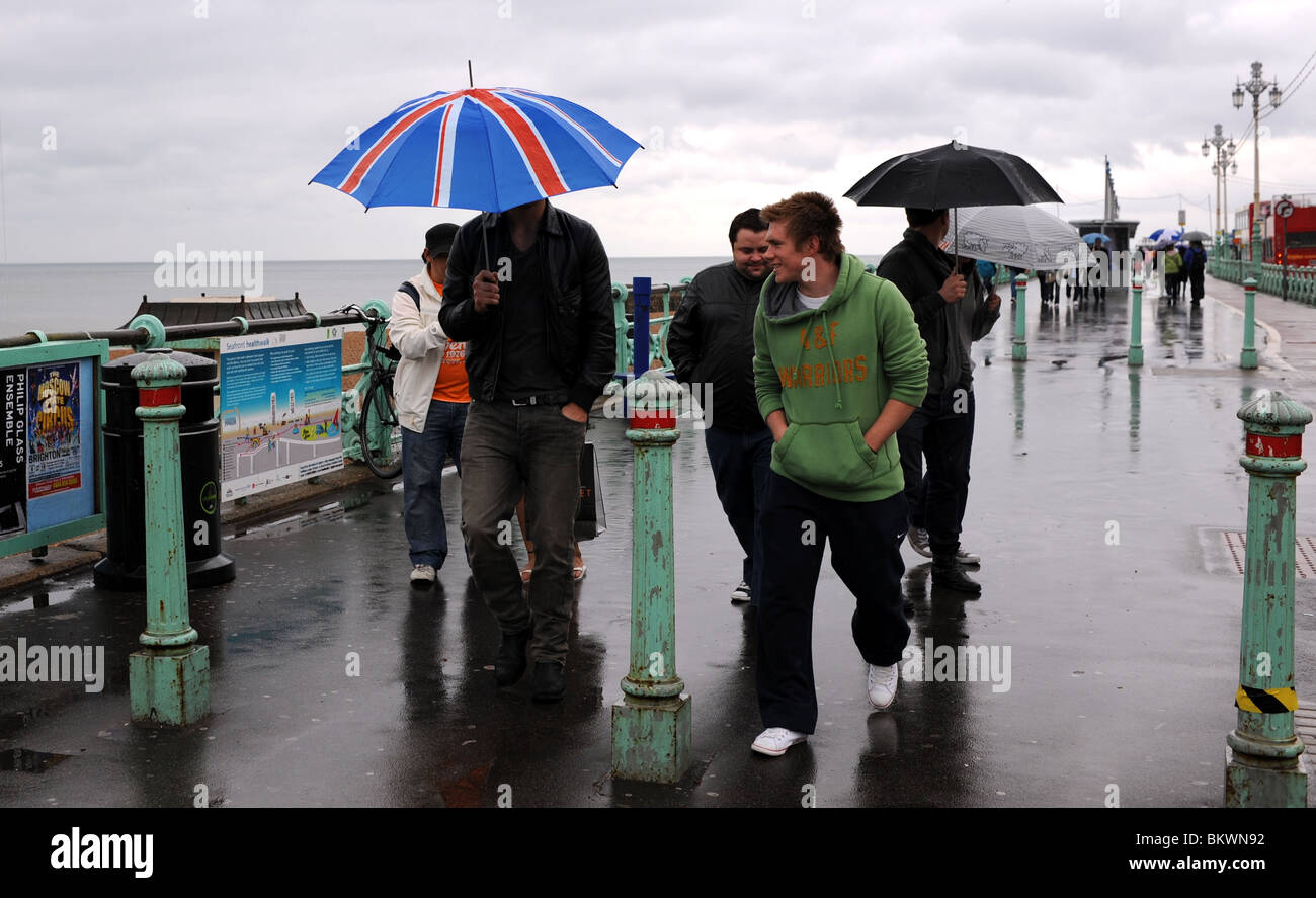 Visitors to Brighton seafront with umbrellas battle against wind and ...
