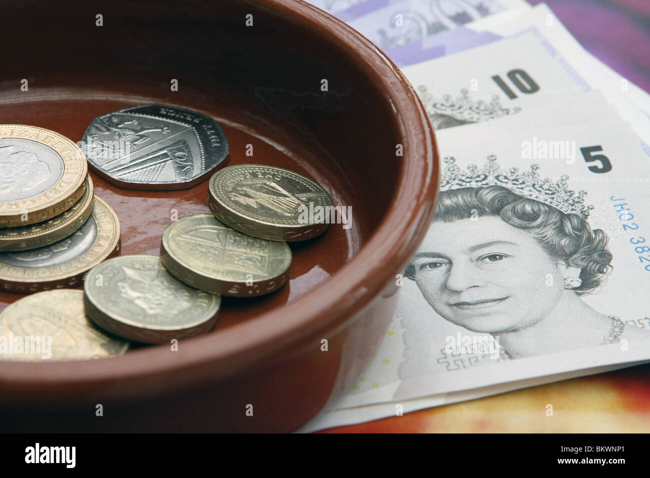 sterling notes under a brown dish containing sterling coins Stock Photo ...