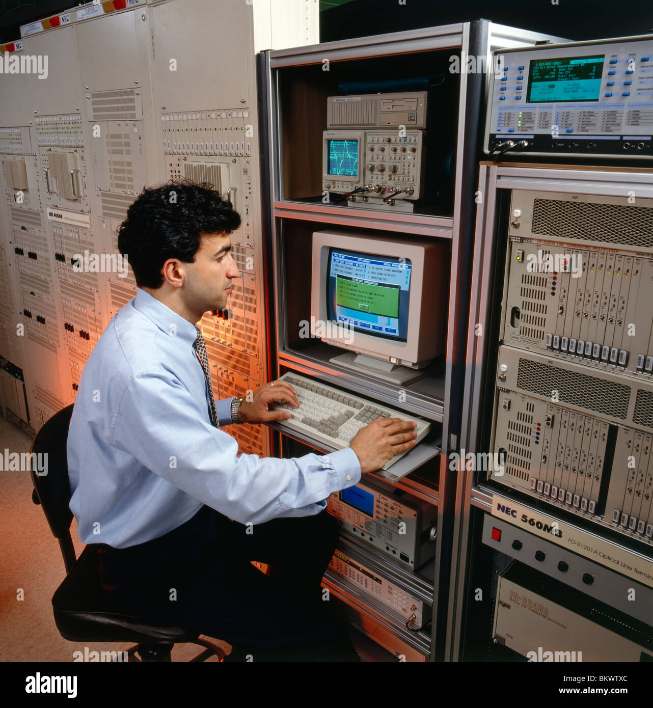 Male engineer using computers to diagnose and repair telecommunications ...
