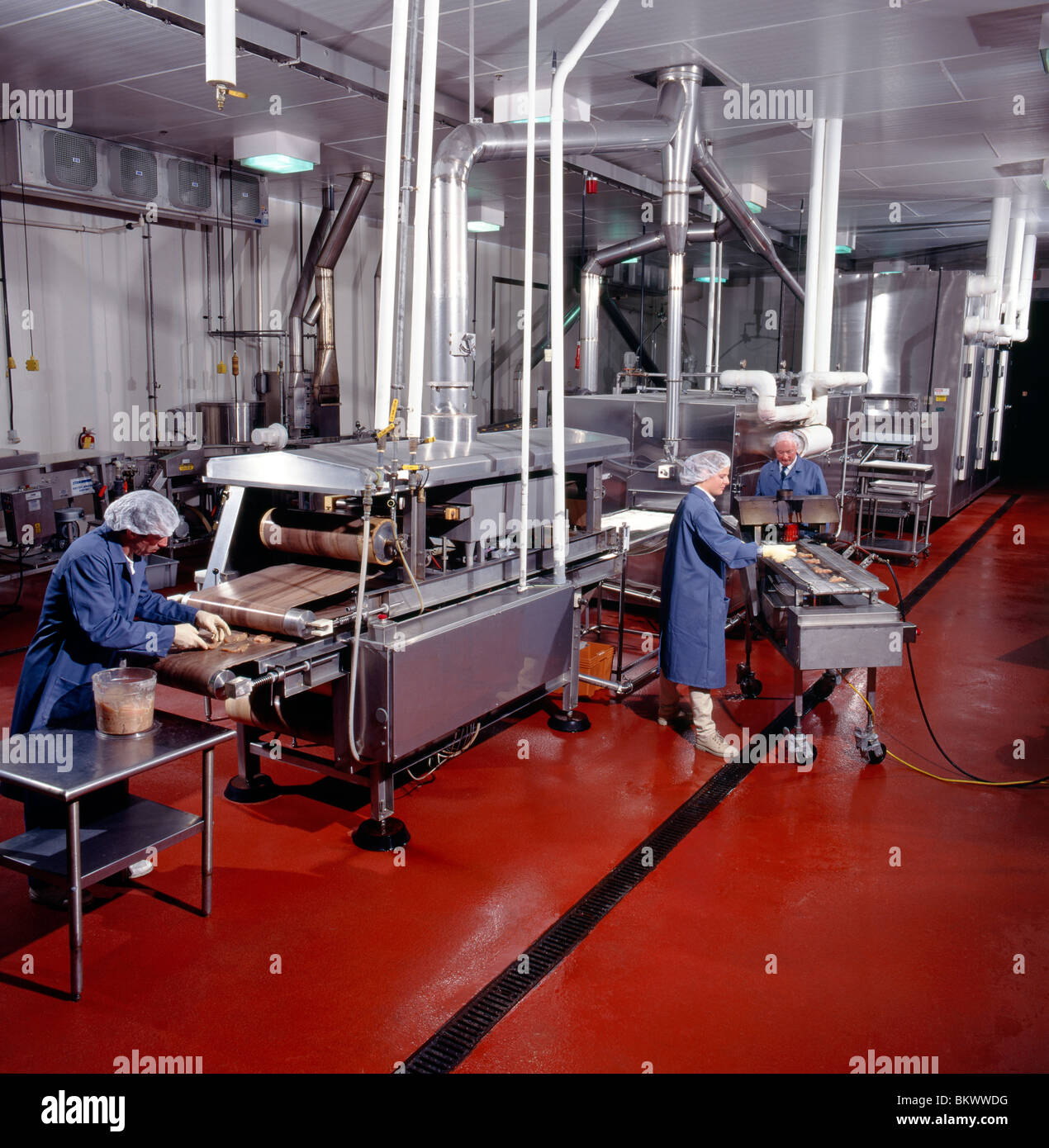 Workers at an automated stainless steel assembly line produce hamburger ...