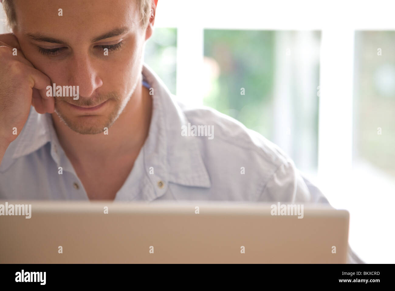 Close up of young man looking at laptop computer screen Stock Photo - Alamy