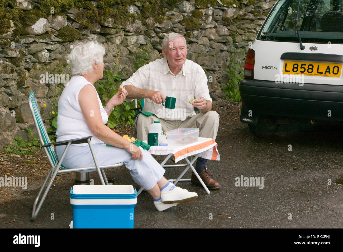 An elderly couple having a picnic in a layby in Grasmere Lake district ...