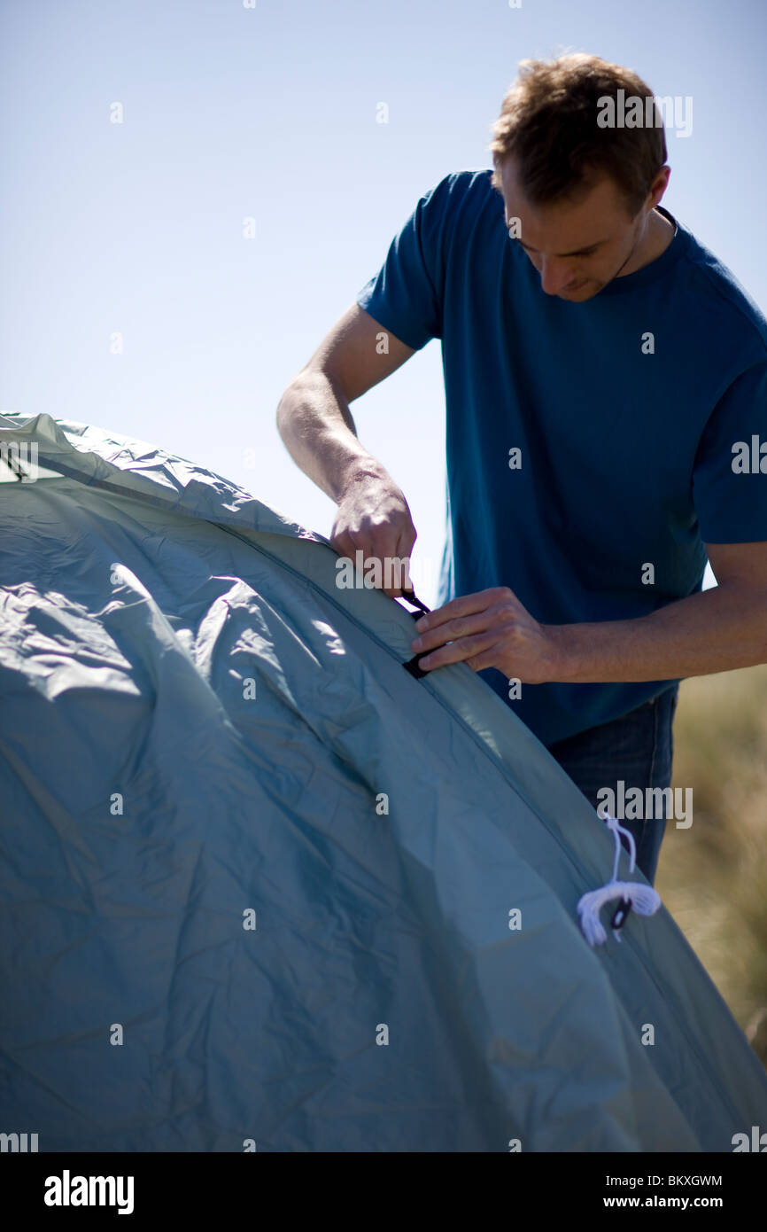 Portrait of young man standing and erecting tent Stock Photo - Alamy