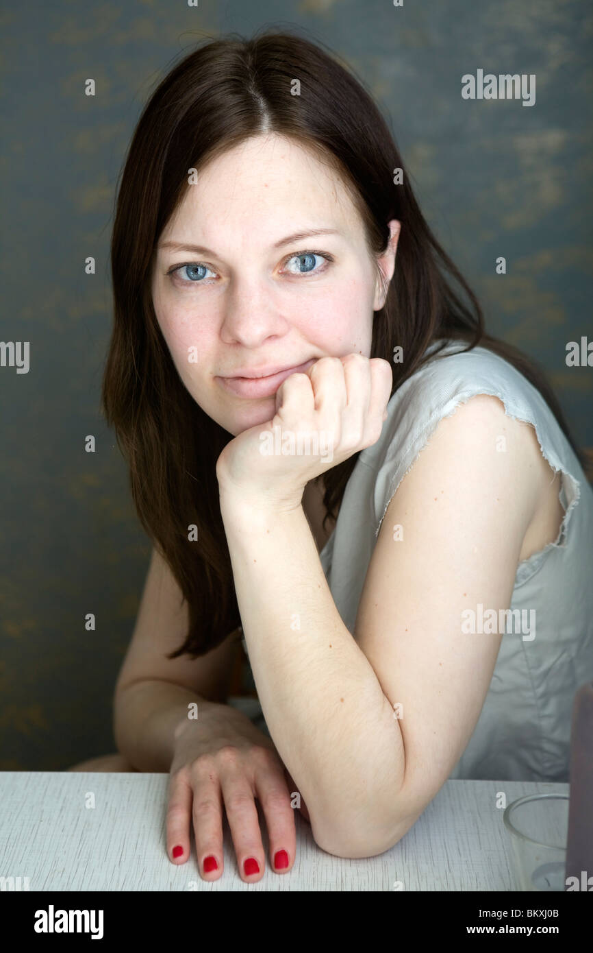 young serious woman sitting at the table Stock Photo - Alamy