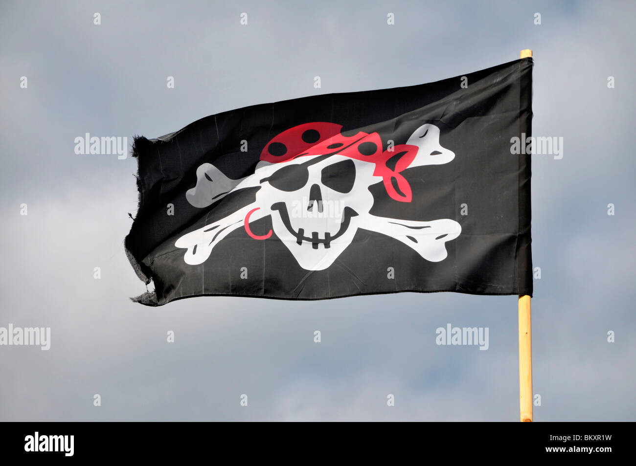 a black pirate skull and cross bone flag flying from a mast Stock Photo ...