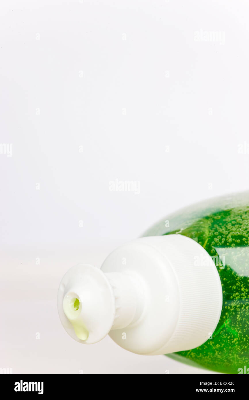 Close up of a plastic bottle with green dishwashing detergent spilling ...