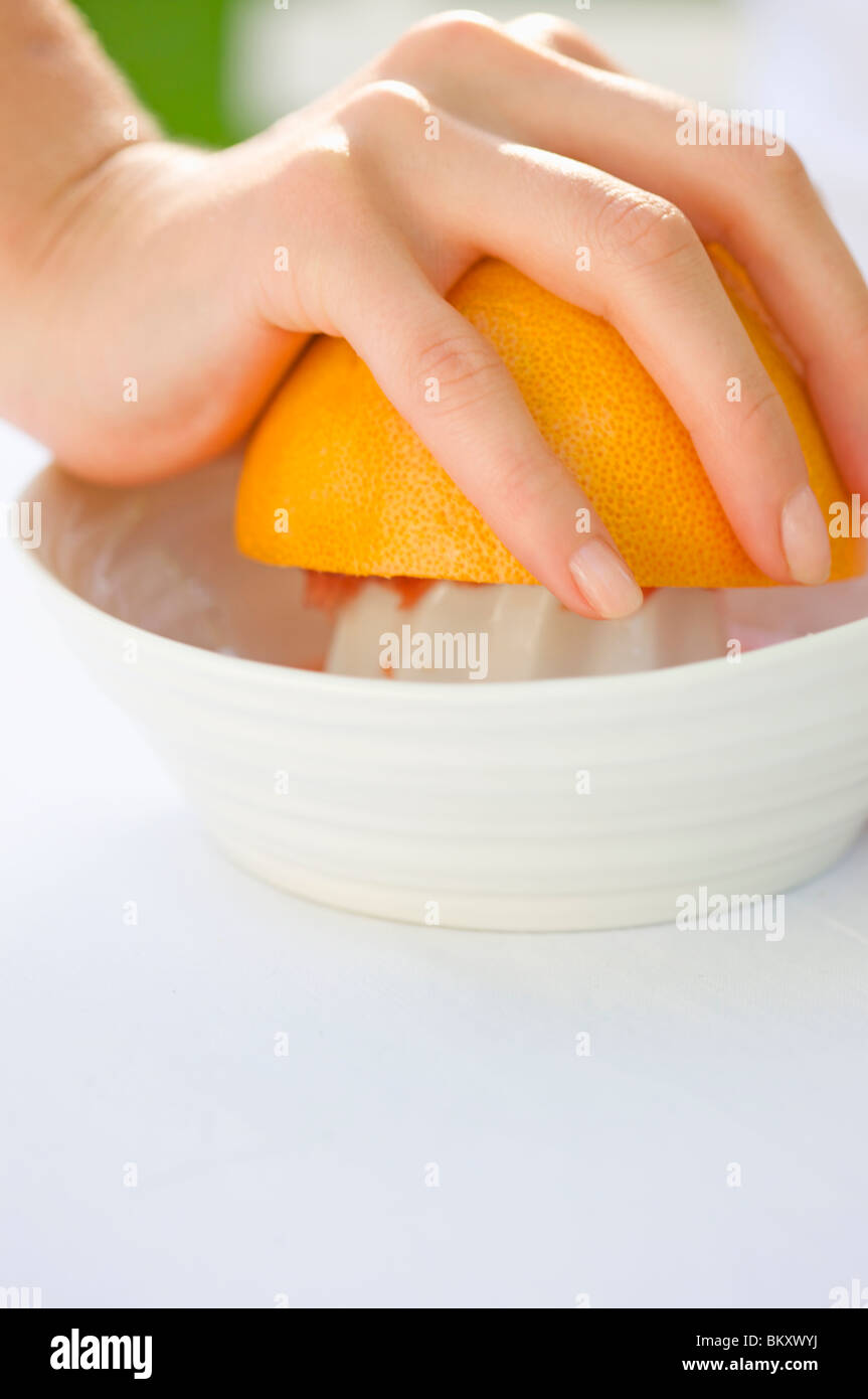 Orange juice, one hand squeezing one half orange, orange slices on a ...