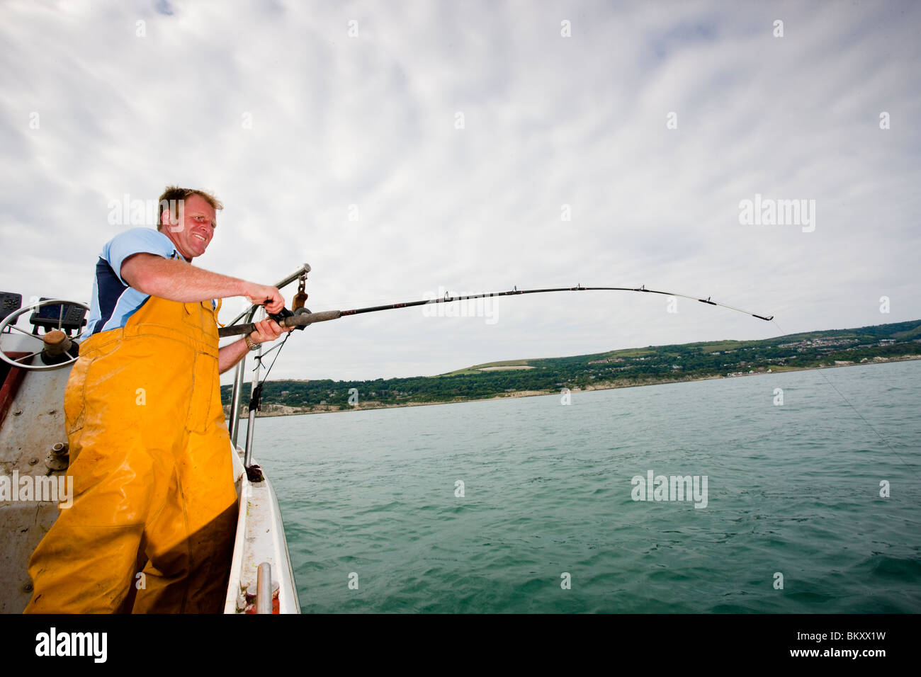 Profile of a fisherman standing in a boat fishing Stock Photo - Alamy