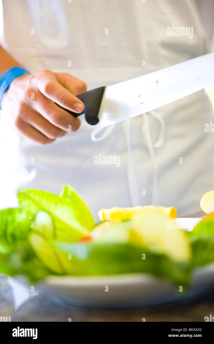 Chef's hand holding a knife standing behind a plate of salad Stock ...
