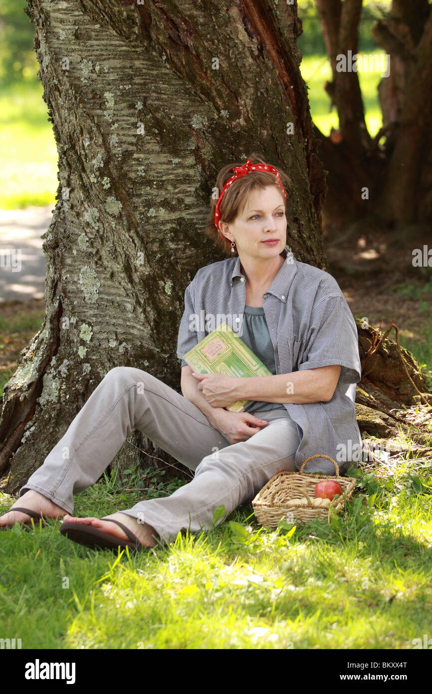 woman under tree relaxing with book Stock Photo - Alamy