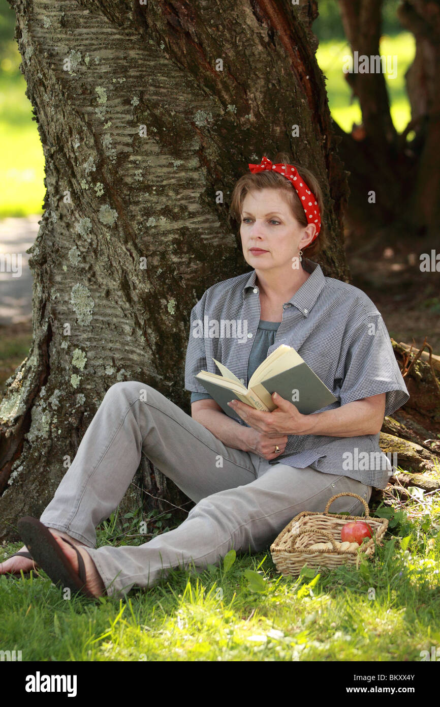 woman under tree relaxing with book Stock Photo - Alamy