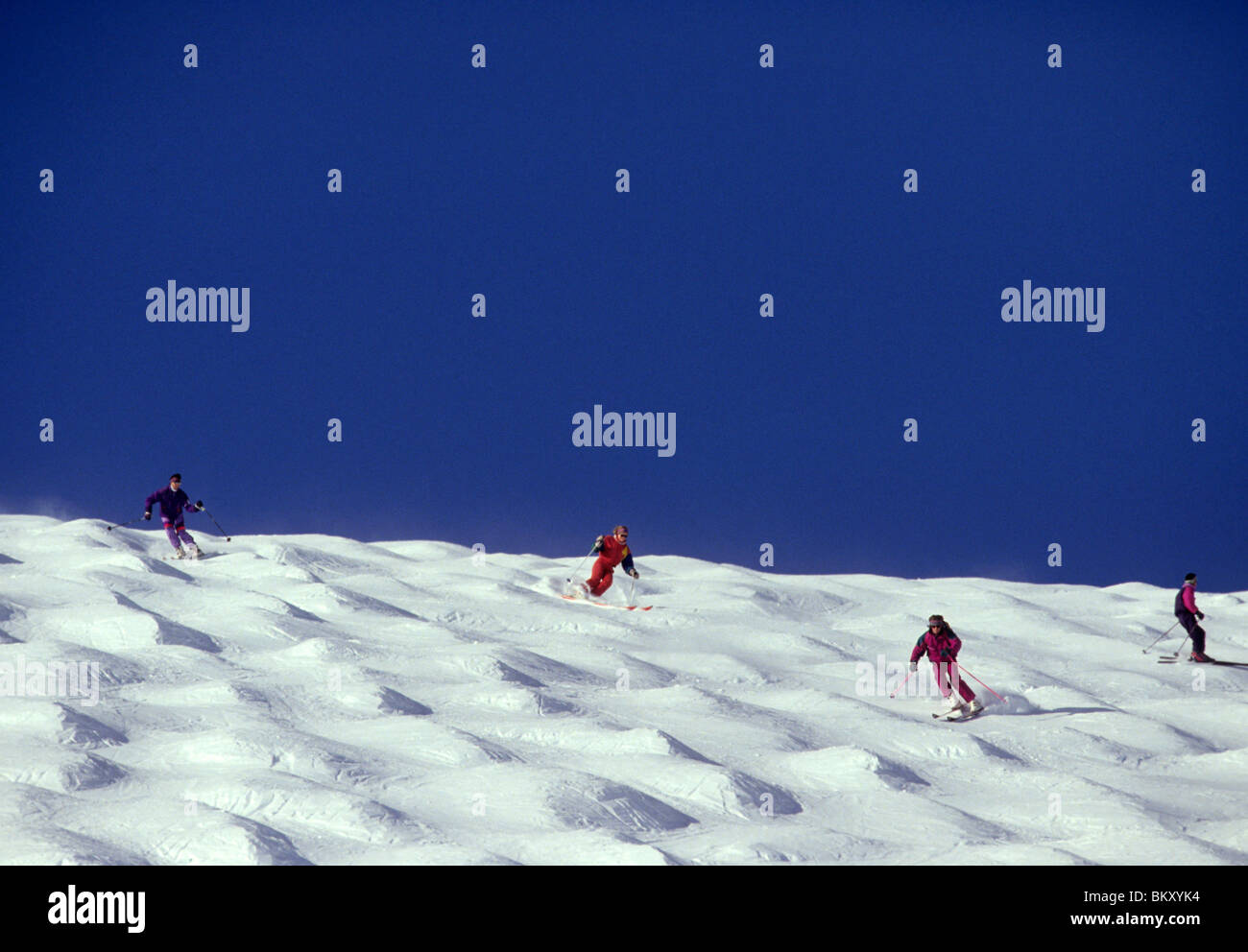 Skiers going over moguls on slope Stock Photo - Alamy
