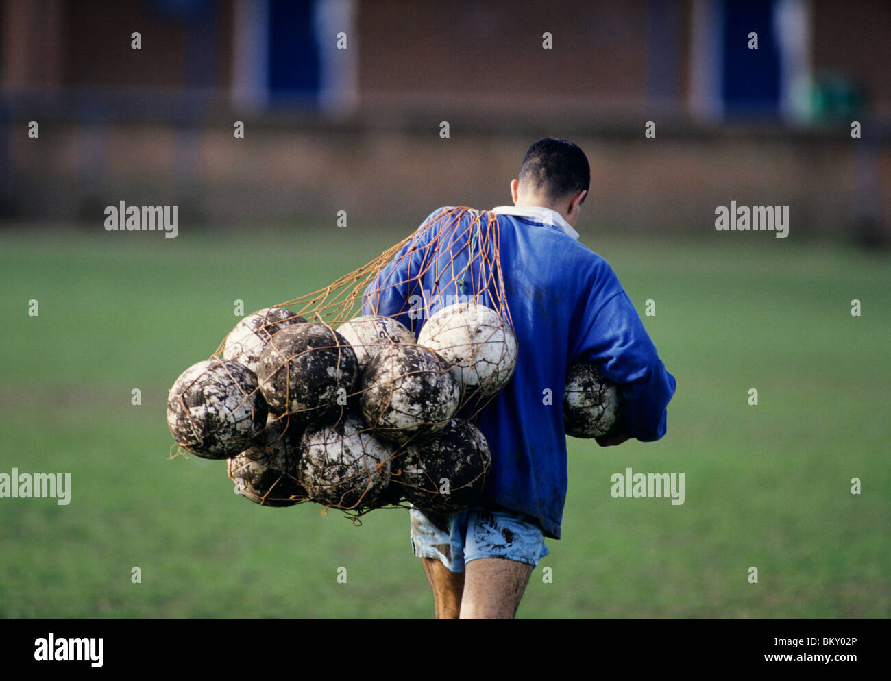 Man carrying bag of muddy footballs Stock Photo - Alamy