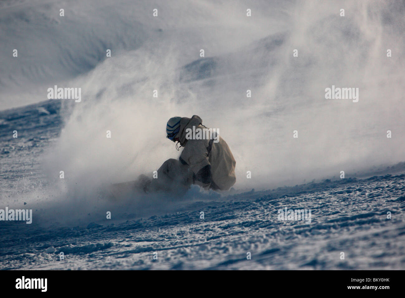 Person snowboarding down slope making spray Stock Photo - Alamy
