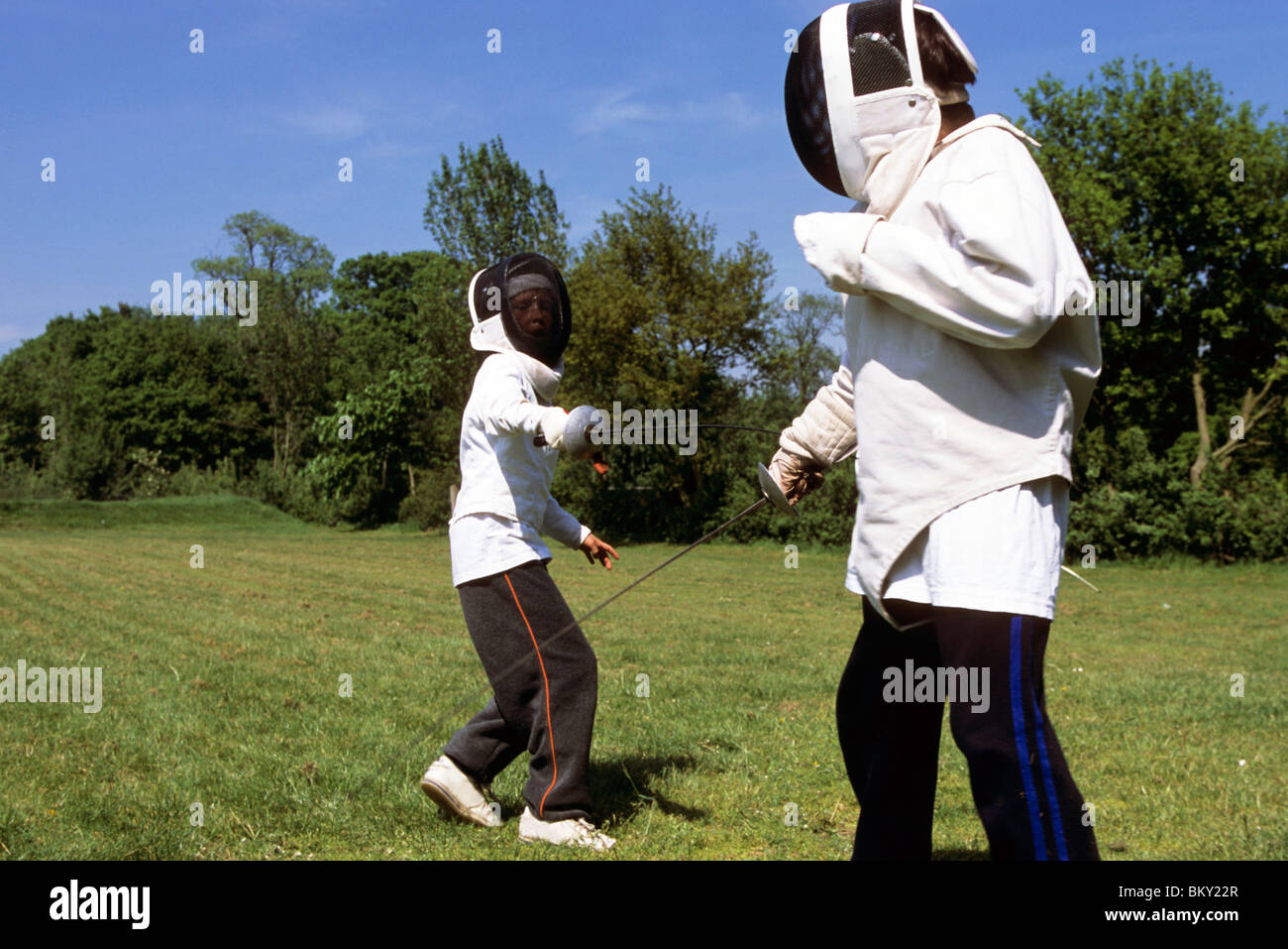 Two boys fencing in grassy area Stock Photo - Alamy