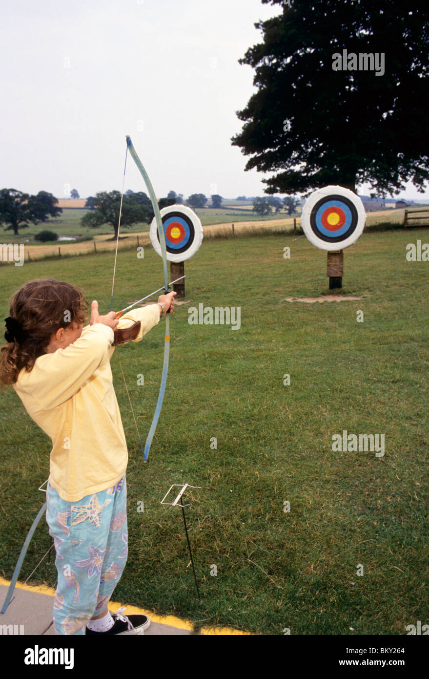 Girl aiming bow and arrow at target Stock Photo - Alamy