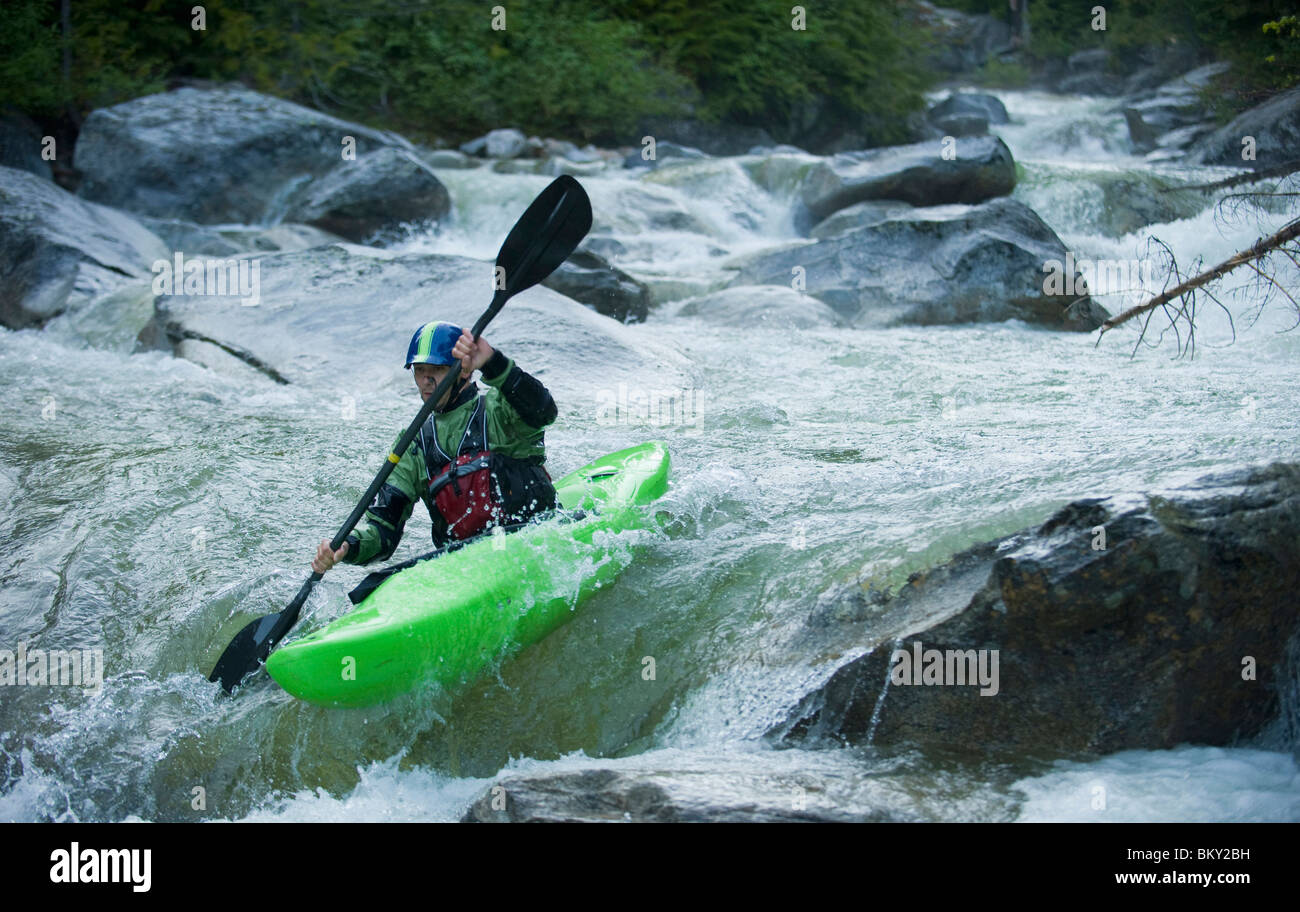 A whitewater kayaker continues down a rocky section of a high moutain ...