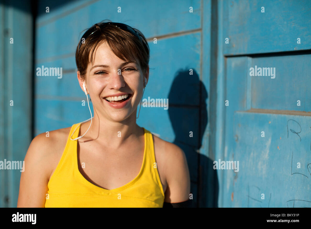 Woman in her late 20's wearing her workout clothes and headphones looks ...