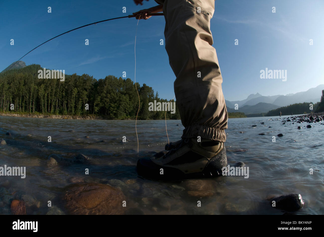 A man in waders casts into a river while fly fishing in Squamish ...