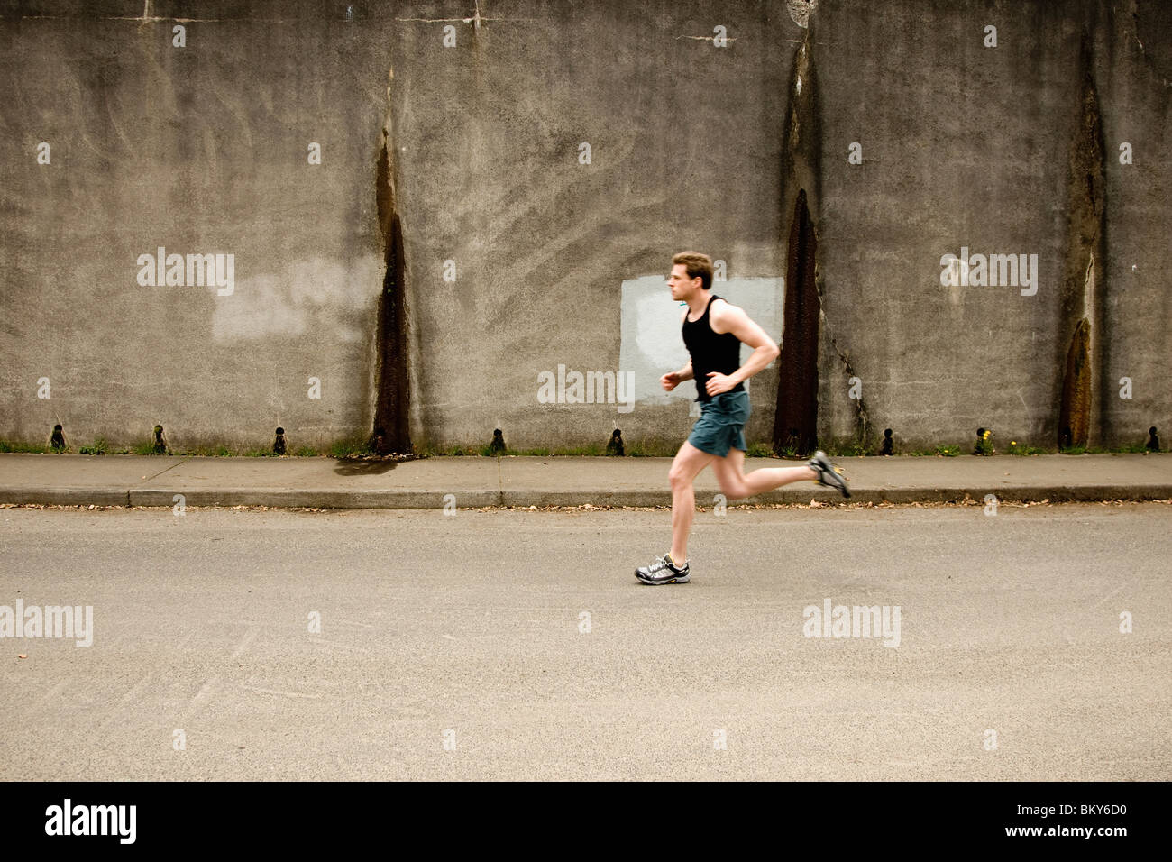 An athletic man jogging past a concrete wall in Portland, Oregon Stock ...