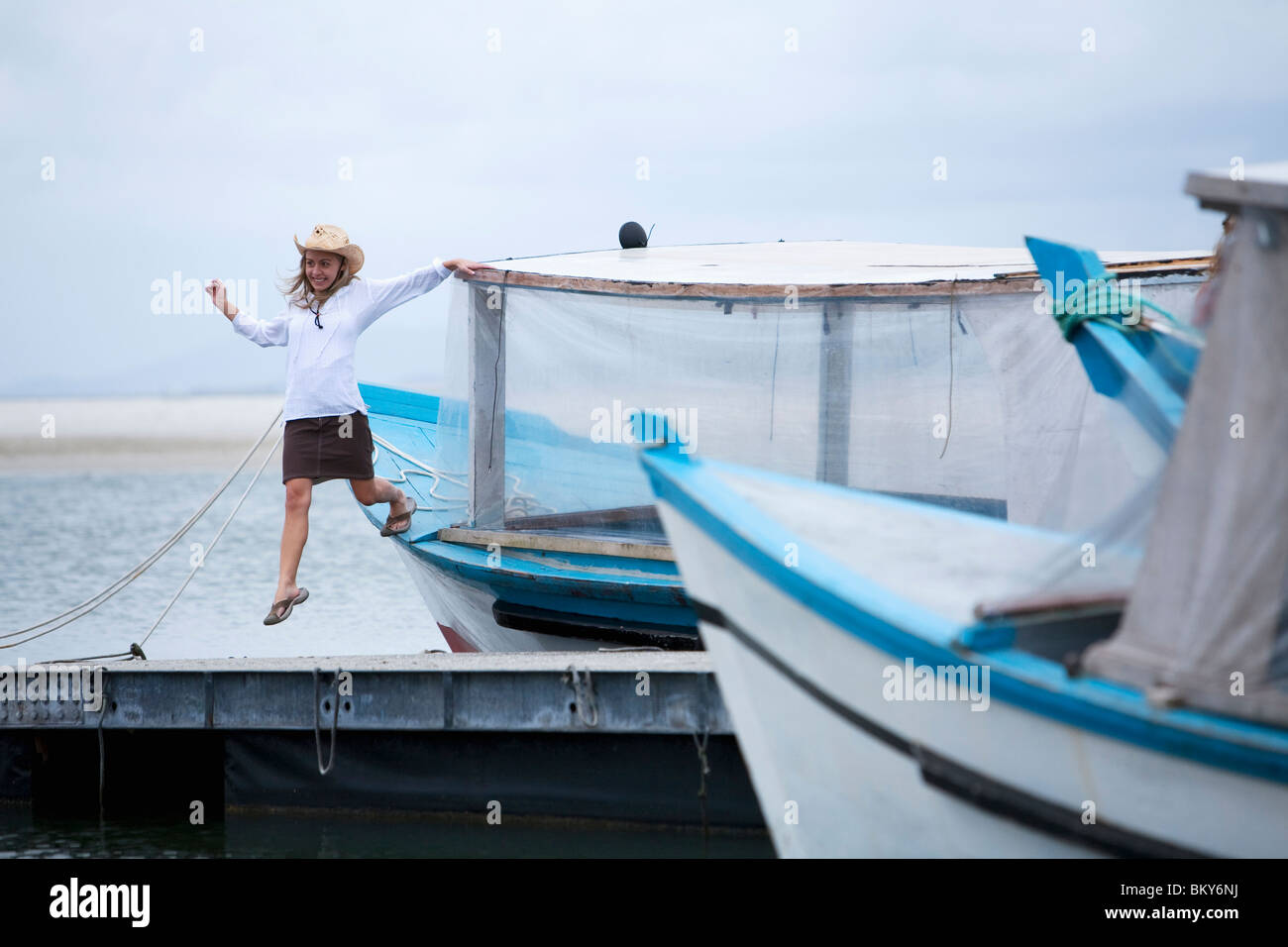 A woman leaps off of a boat onto a dock in Brazil Stock Photo - Alamy