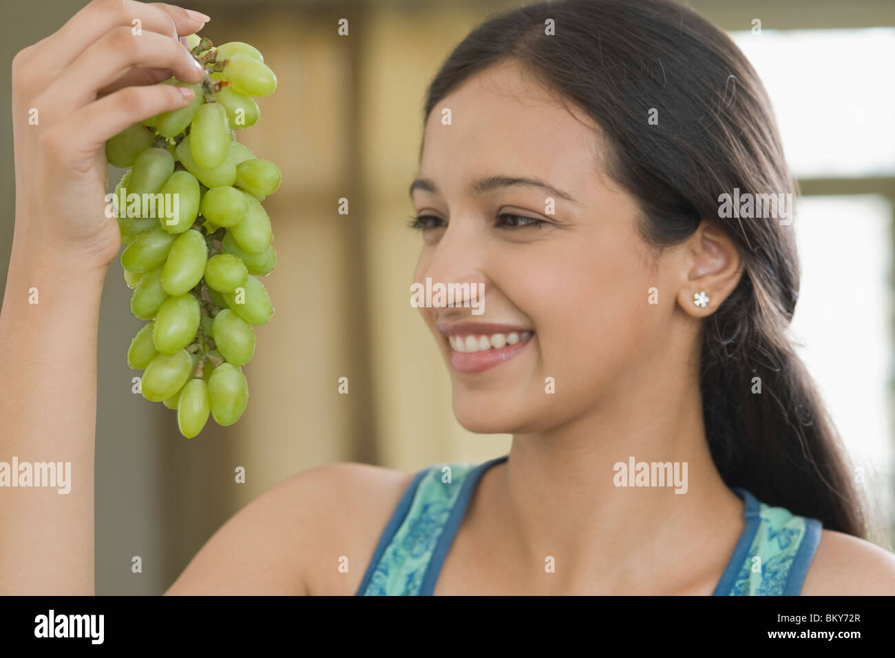 Woman holding a bunch of green grapes and smiling Stock Photo - Alamy