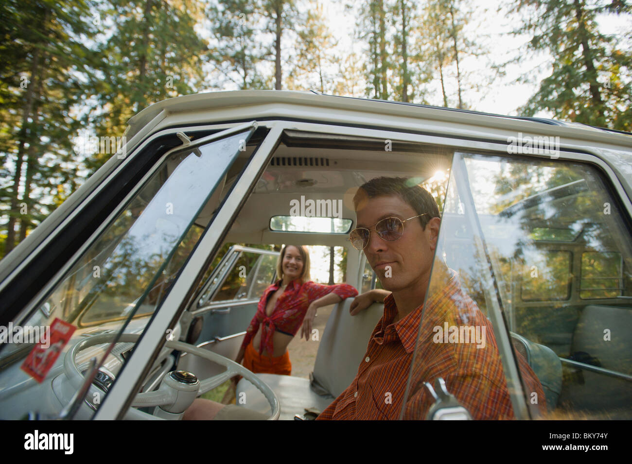 A young man in sun glasses offers a woman a ride in a vintage van Stock ...