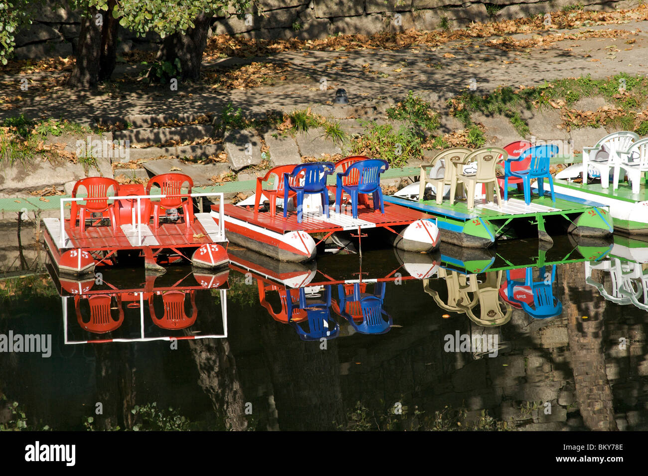 Colourful river rafts with picnic chairs moored to the stone banks of ...