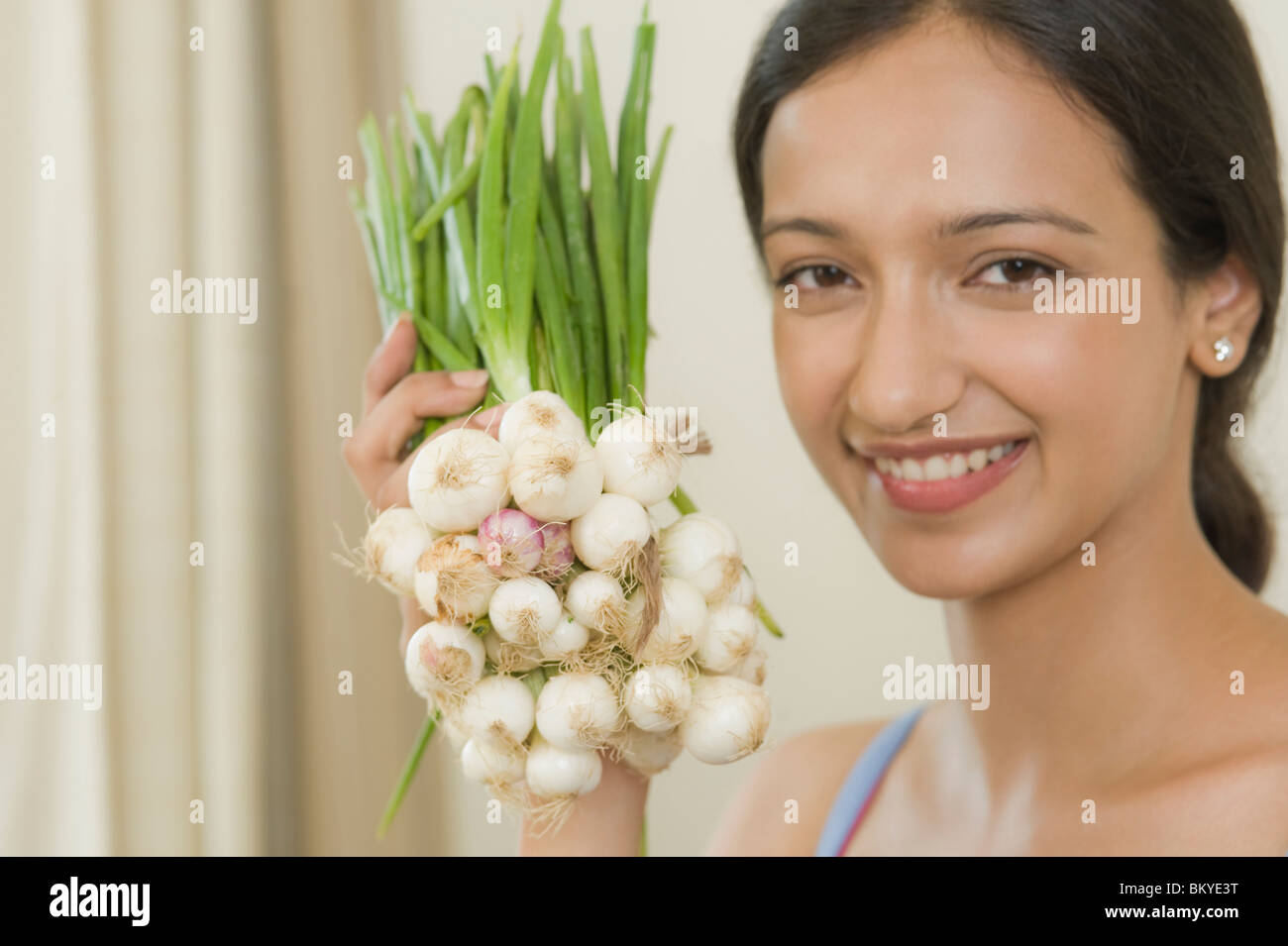 Woman holding a bunch of spring onions and smiling Stock Photo - Alamy