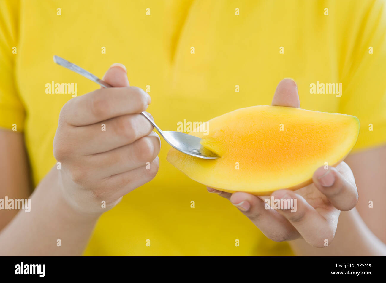 Woman eating mango with a spoon Stock Photo - Alamy