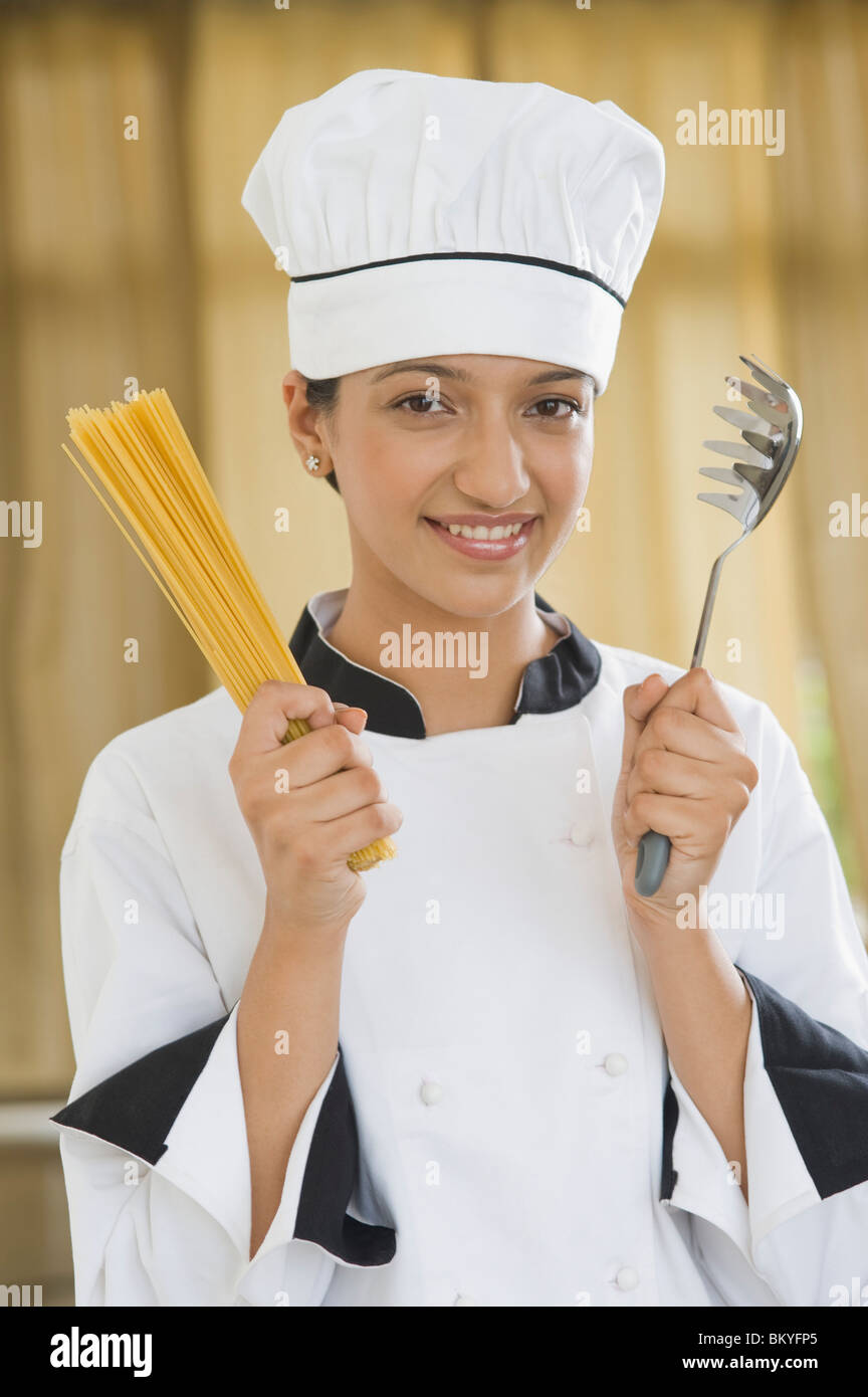 Female chef holding spaghetti and pasta spoon Stock Photo - Alamy