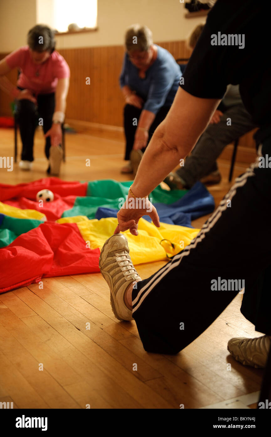 senior citizens participating in a low-impact chair aerobics class in a ...